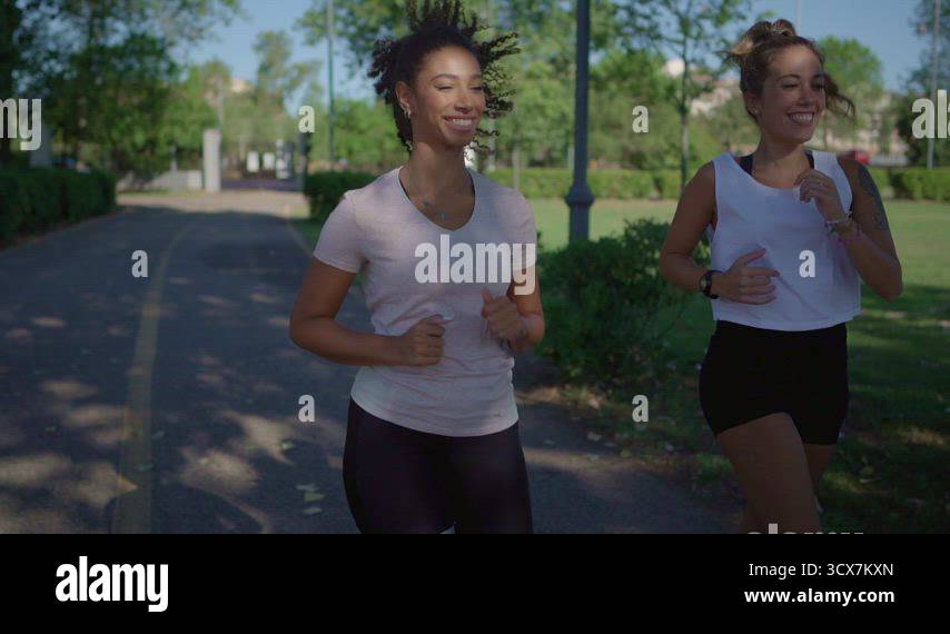 Two young cute women caucasian and hispanic jogging at the park to keep ...