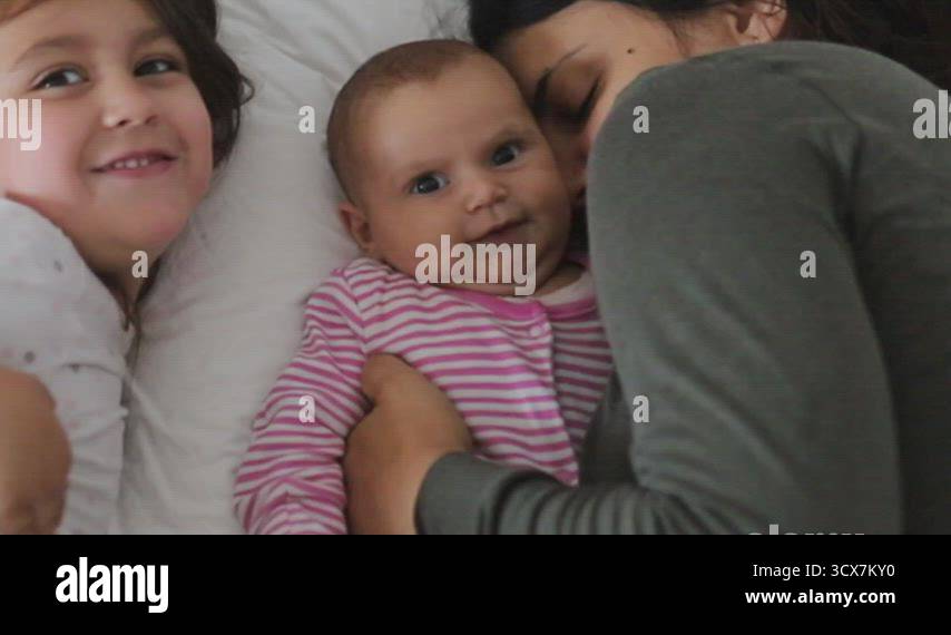 Mother Resting on a Bed with Her Two Happy Young Daughters Stock Video ...