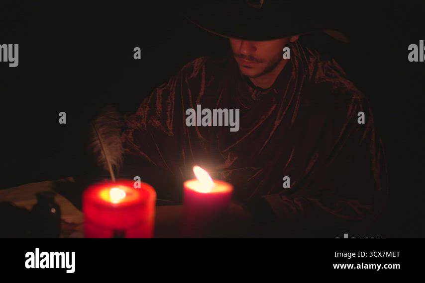 Wizard writing on paper with feather pen and ink. Lit up by candles ...