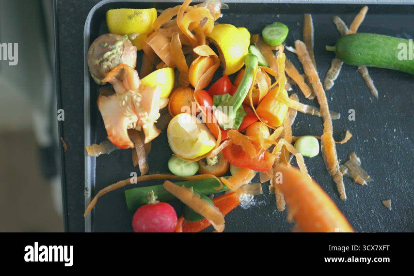 Female hands gently peeling a carrot on top of organic trash Stock ...