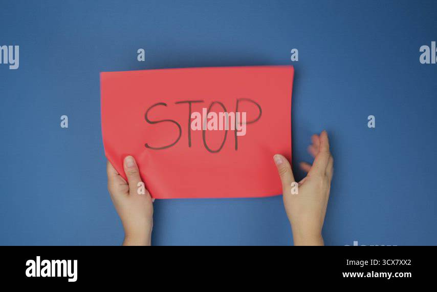 female hands hold a red sheet of paper with the inscription stop, blue ...