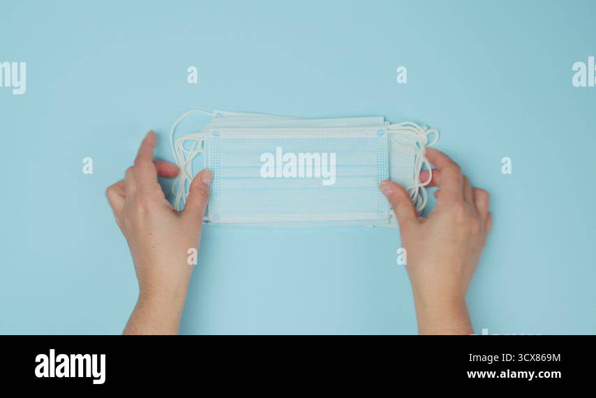 two female hands hold a stack of disposable face masks on a blue table ...