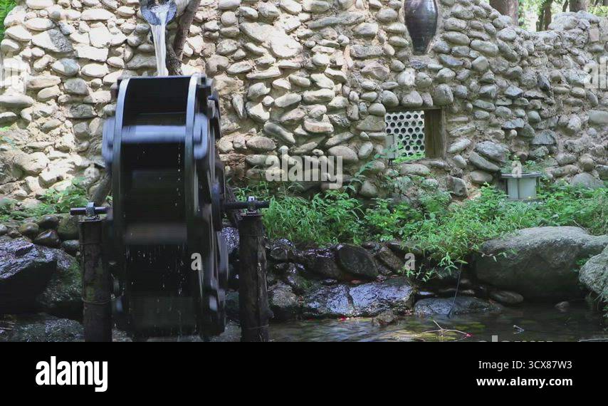 Old style vintage water wheel or water mill with flowing water in a ...