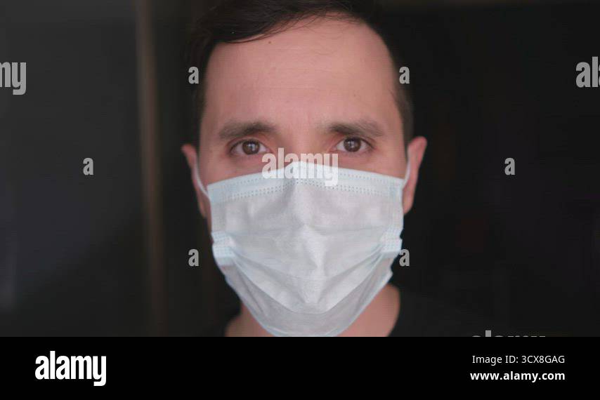 A smile. Close-up portrait of a young guy in a medical mask standing on ...