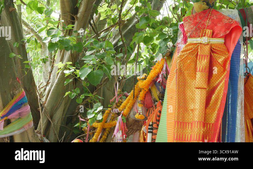 Colorful offering clothes on tree near altar. Bunch of bright ...