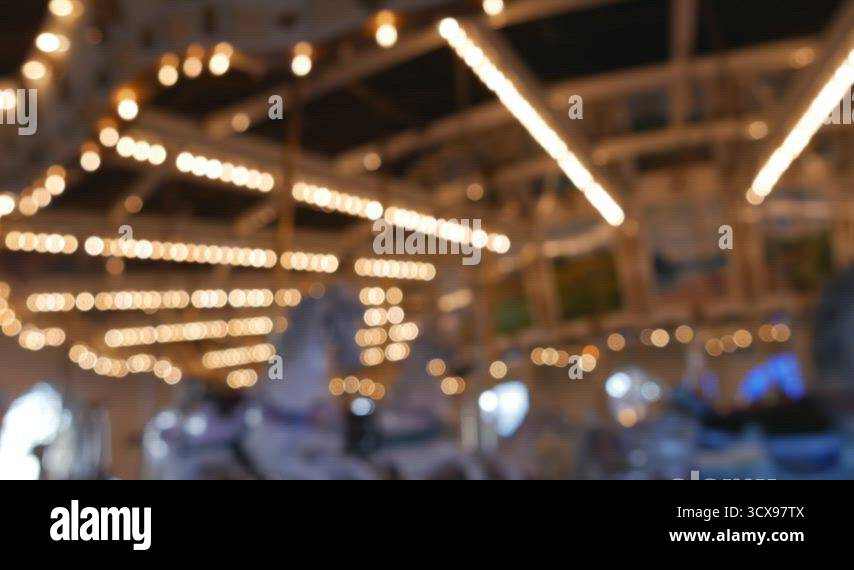Golden illuminated defocused retro carousel turning in amusement park ...