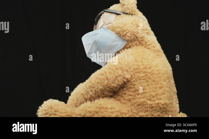 brown teddy bear sits in protective plastic glasses, a medical ...