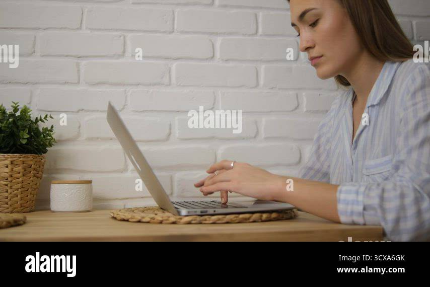 A girl in a striped pejama, at home. Works remotely behind a computer ...