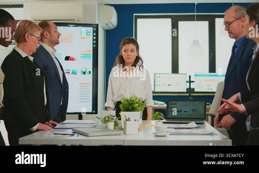 Diverse team of workers talking, looking at documents and analyzing ...