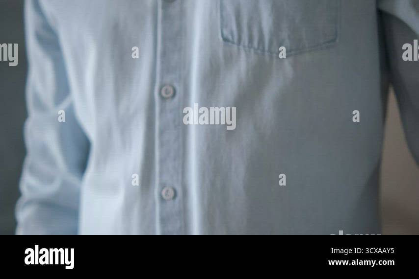 The businessman buttons up the sleeves of his shirt in close-up. A ...