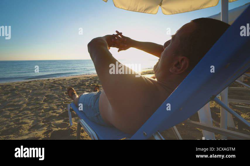 Male hands play with sun on sunset sky lying on beach. Concept of ...