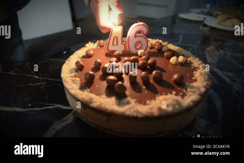 Female hand lighting candles on cake for 46 years old man birthday ...