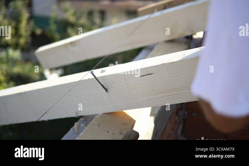 construction roofer carpenter worker nailing wood board with hammer on ...