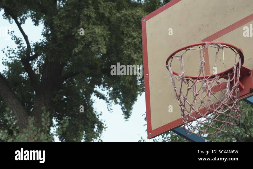 Close up of orange basketball hitting the basket on a street court in ...