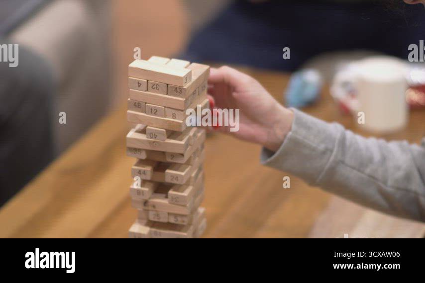 Group of multiethnic happy friends playing block removal game and ...
