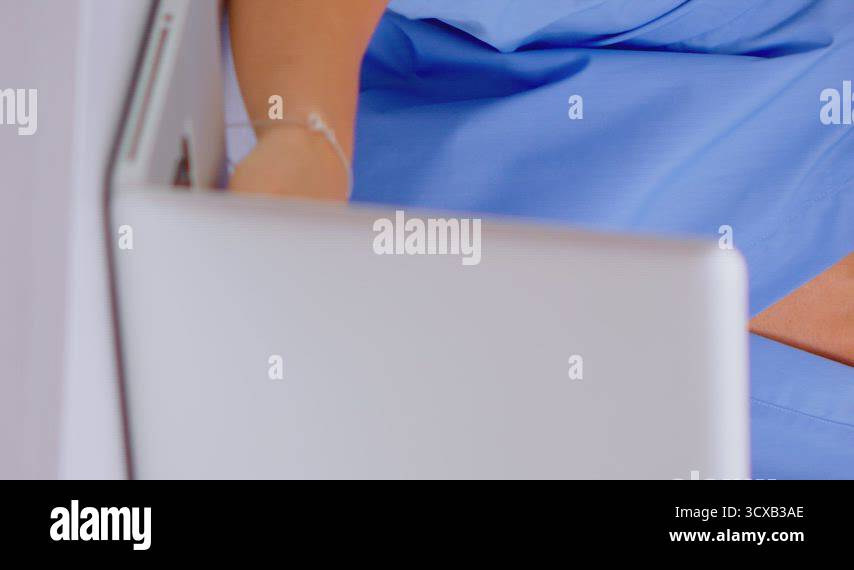 Vertical video: Close up of young medical assistant typing at laptop ...