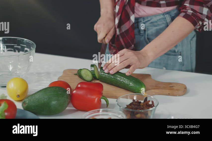 Cutting in slices fresh cucumber on table cooking a lunch or dinner ...