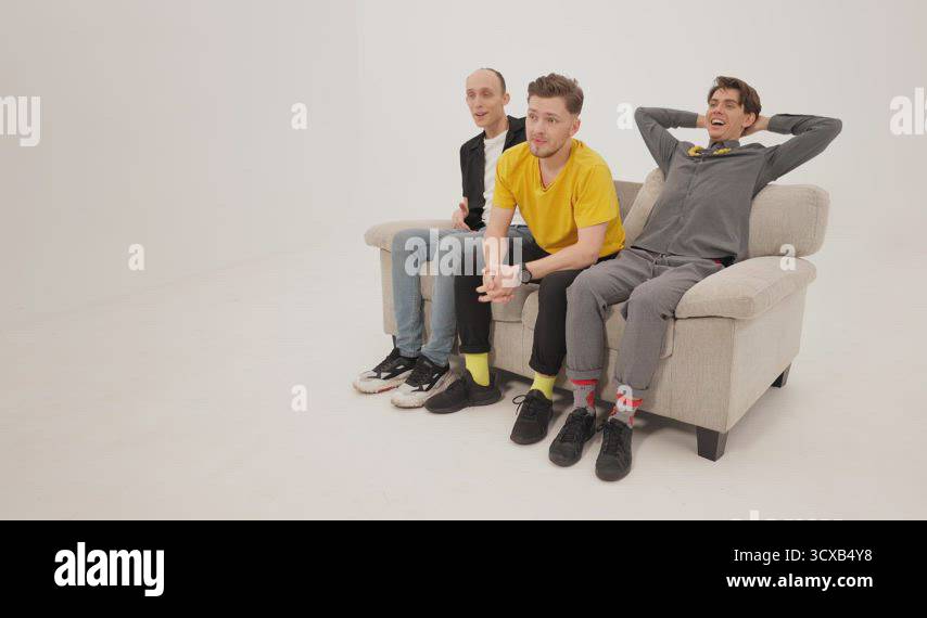 Watching sports channel friends handsome guys sitting on a white sofa ...