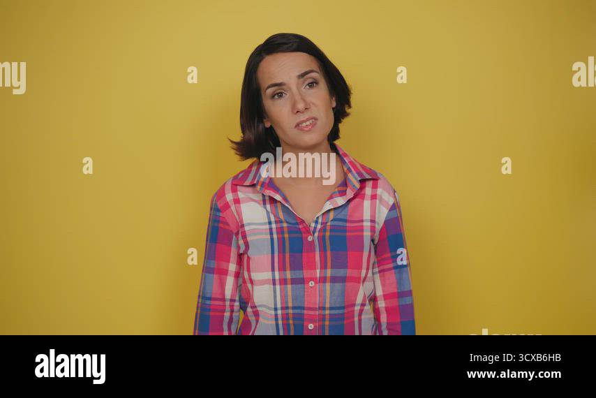 Girl expressing doubt or hesitation looking to camera. Woman in a plaid ...