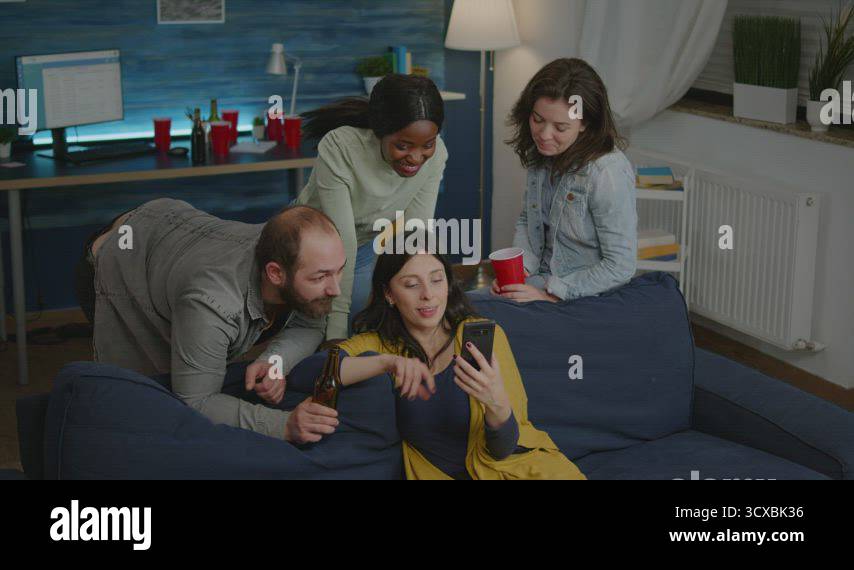 Multiracial friends hanging out late at night watching funny ...