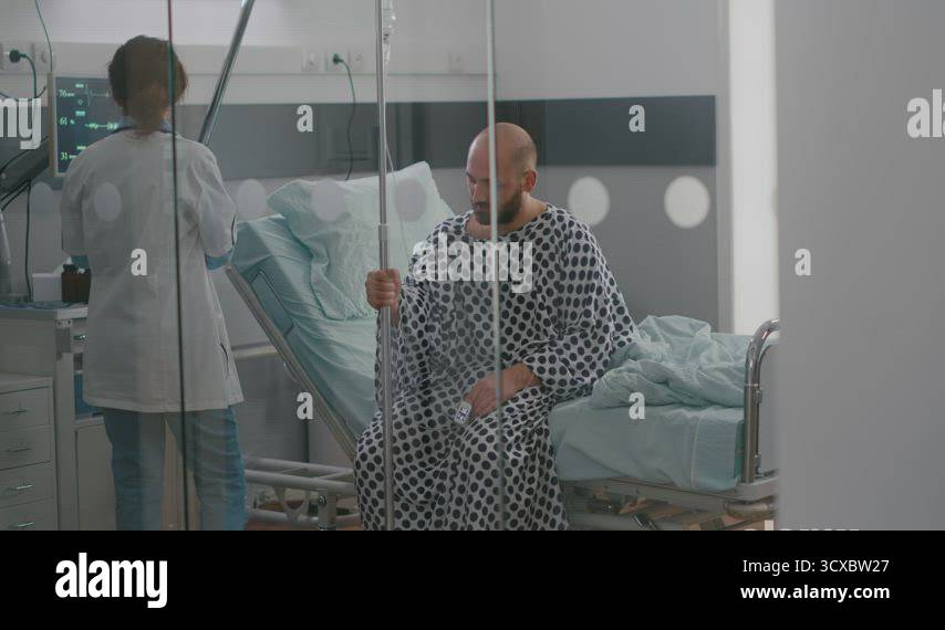 Practitioner doctors helping patient to stand up from bed holding ...