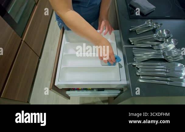 Top view of woman cleaning cutlery organizer with a cloth and placing ...