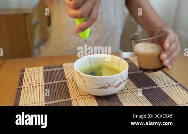 Close-up video of a person frothing matcha tea with an electric whisk ...