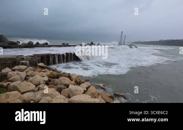 Massive storm waves crashing over a pier with seawater flooding the ...