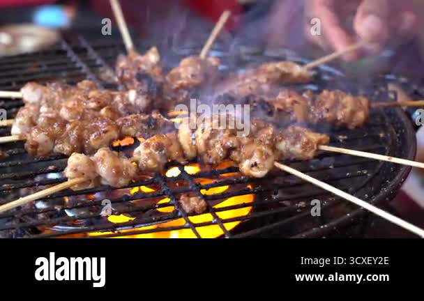 Street vendor sells grilled chicken meat at street food market in ...