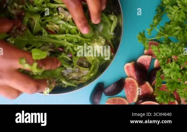 hands of male chef preparing healthy green salad with figs in kitchen ...