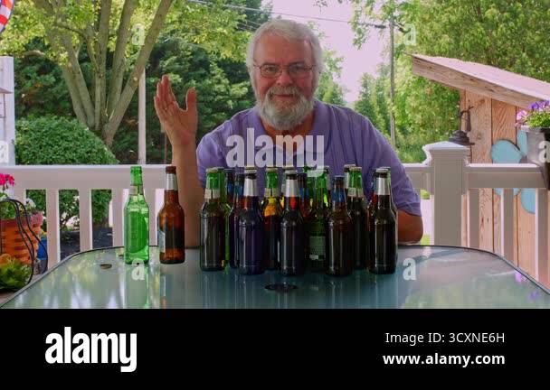 A cheerful man sits at a table outside, waving while surrounded by ...