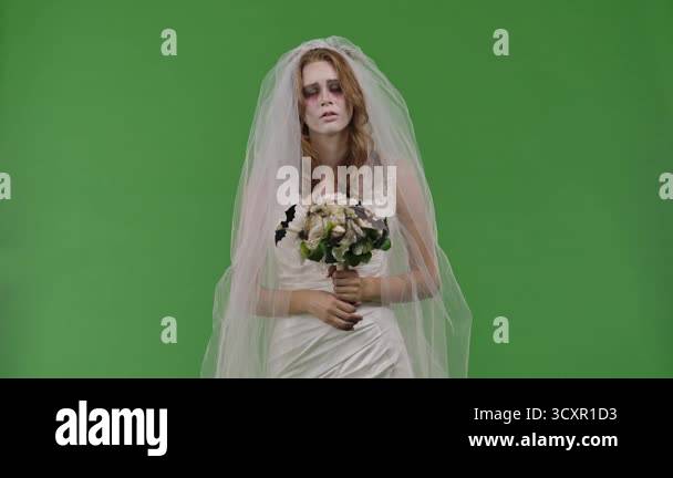 A woman dressed as a dead bride, in a white wedding dress and veil ...