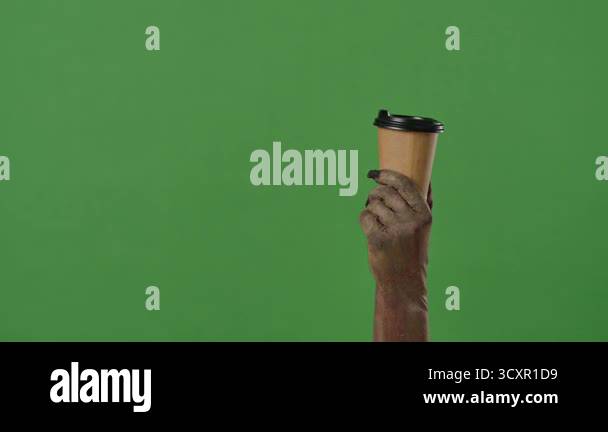 A creepy zombie hand holds a coffee cup, covered in dirt and decaying ...