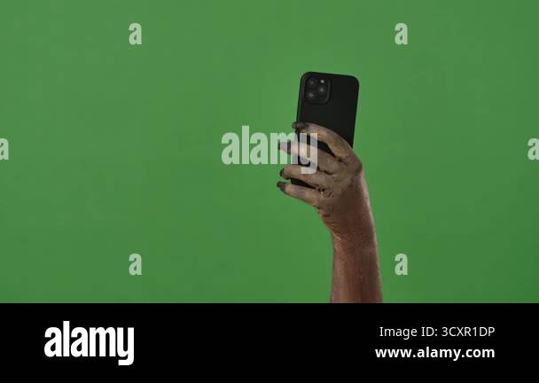 A creepy zombie hands holds a credit card and smartphone, covered in ...