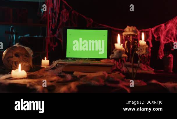 A spooky Halloween scene with a desk featuring a skull, burning candles ...