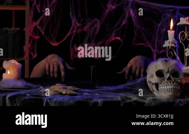 Scary zombie hands open lipstick. A dark room with burning candles, a ...