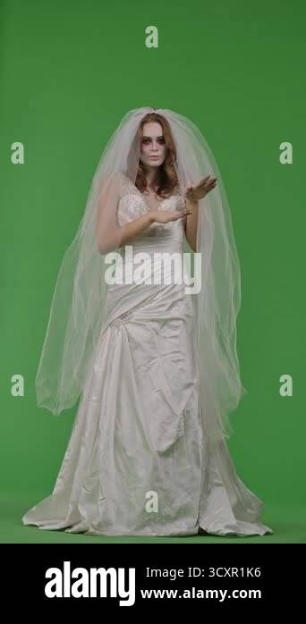 A woman dressed as a dead bride, in a white wedding dress and veil ...