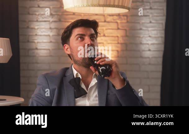 A businessman in a business suit drinks soda from a plastic bottle in a ...