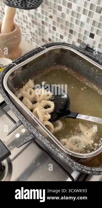 Anonymous person removes rings of sliced, breaded, fried squid from hot ...