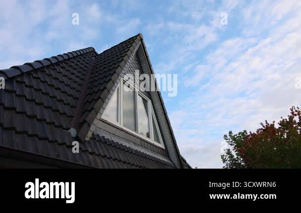 Modern residential house roof with black tiles and a triangular dormer ...