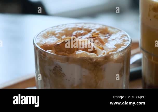 Close up of iced creamy coffee topped with caramelized chunks and foam ...