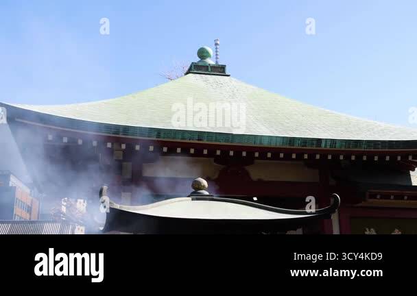 Smoke wafts across a pagoda-style roof against blue sky Stock Video ...