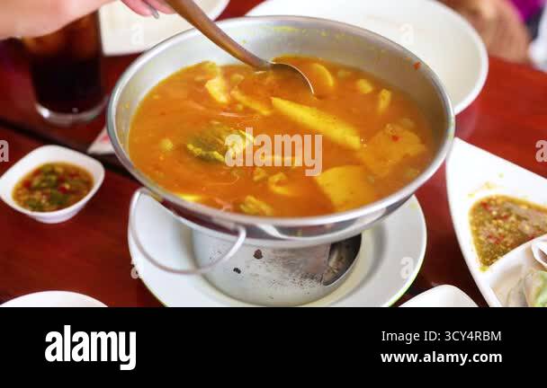 A sequence showing the serving of Kaeng Som soup in a Thai restaurant ...