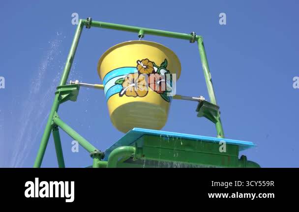 Colorful yellow tipping bucket with floral design at a water park ...
