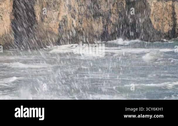 Waves crashing against rock on the shore.Fierce, tumbling white wave ...