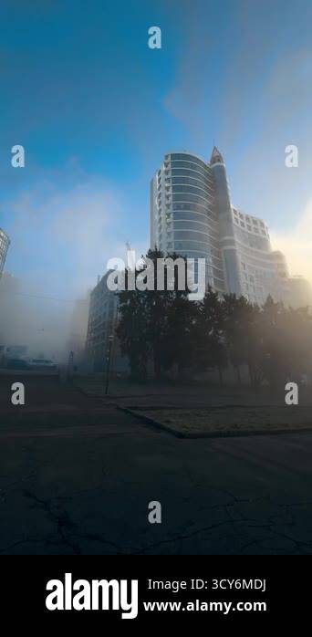 A tall, futuristic building rises above the thick fog that has ...
