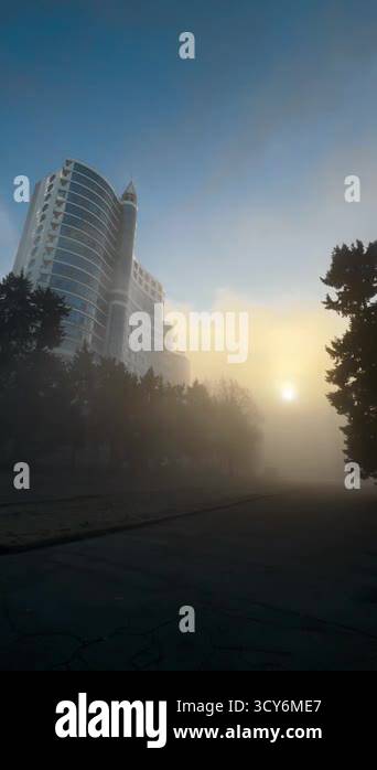 A tall, futuristic building rises above the thick fog that has ...