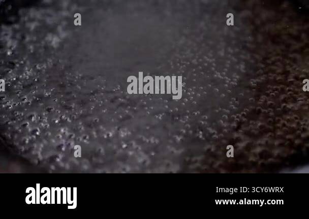 An intense close-up shows water rapidly boiling in a metallic pot, with ...