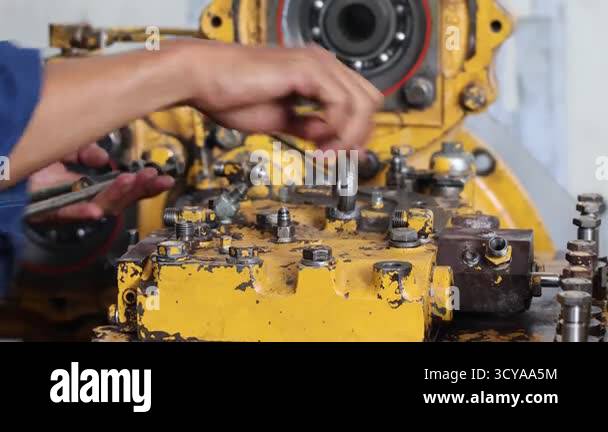 Close-up of mechanics' hands working on a automatic transmission control valve, focusing on the ...
