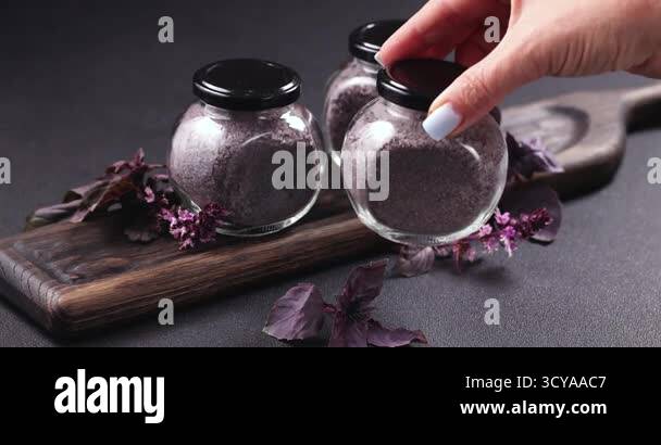 Female hand placing a small glass jar of purple basil salt onto a ...